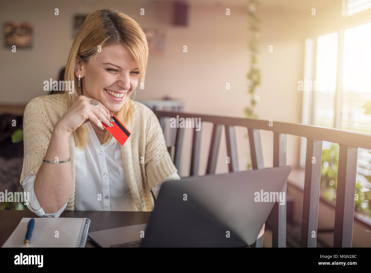Pretty young woman shopping online using her credit card and laptop ...