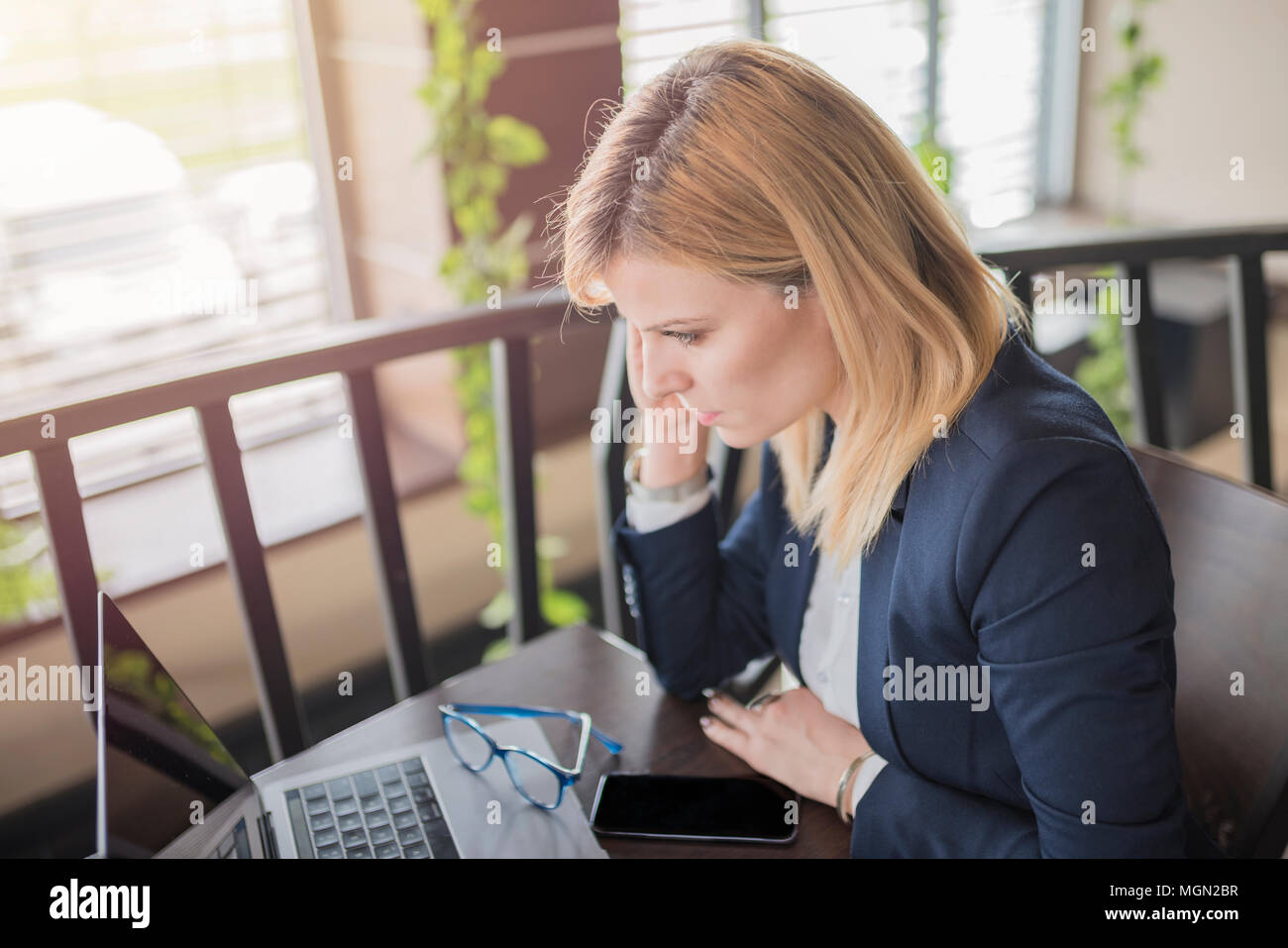 Young nervous business woman using her laptop computer in restaurant ...