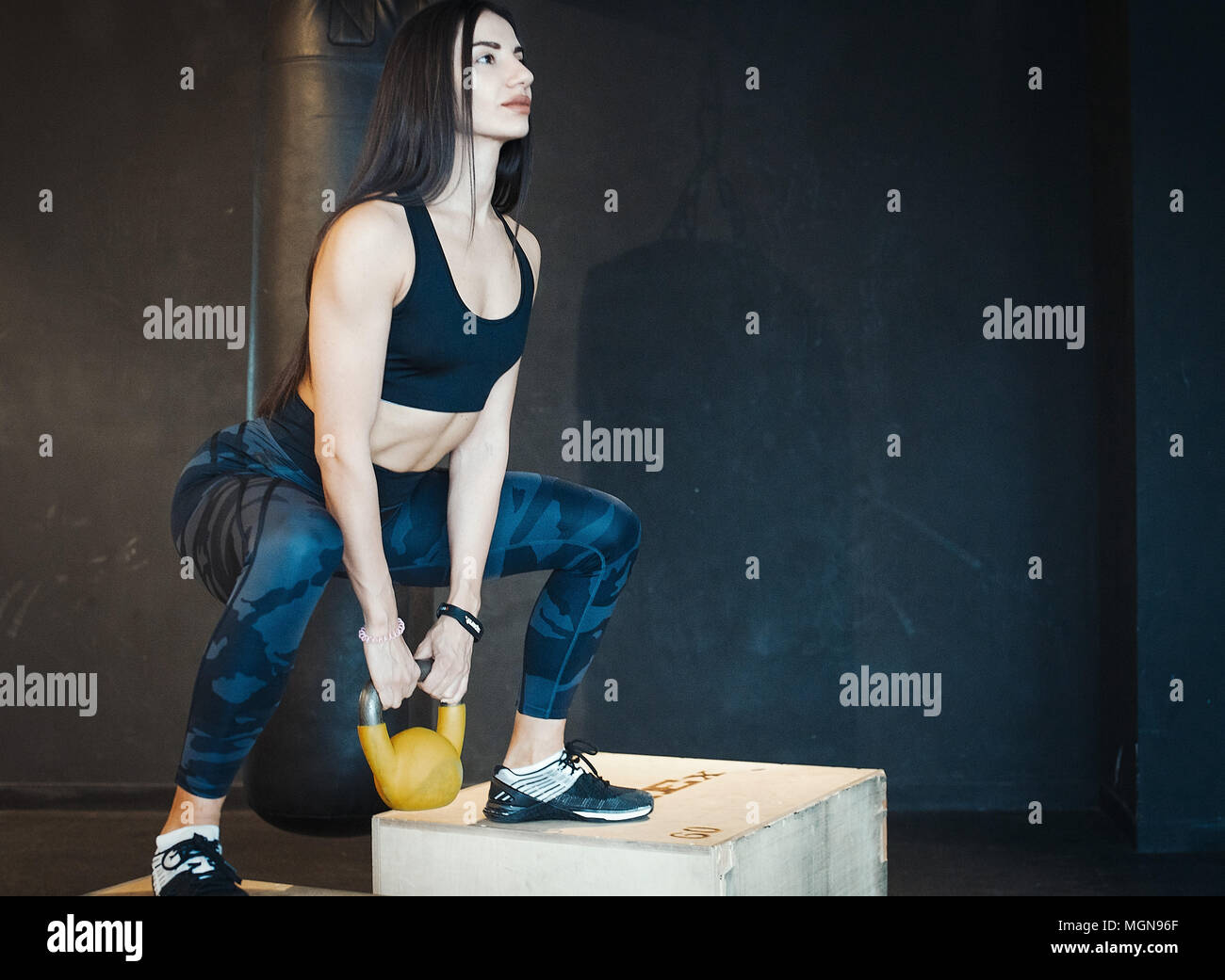 Young attractive brunette girl sit ups with weight on wooden boxes for ...