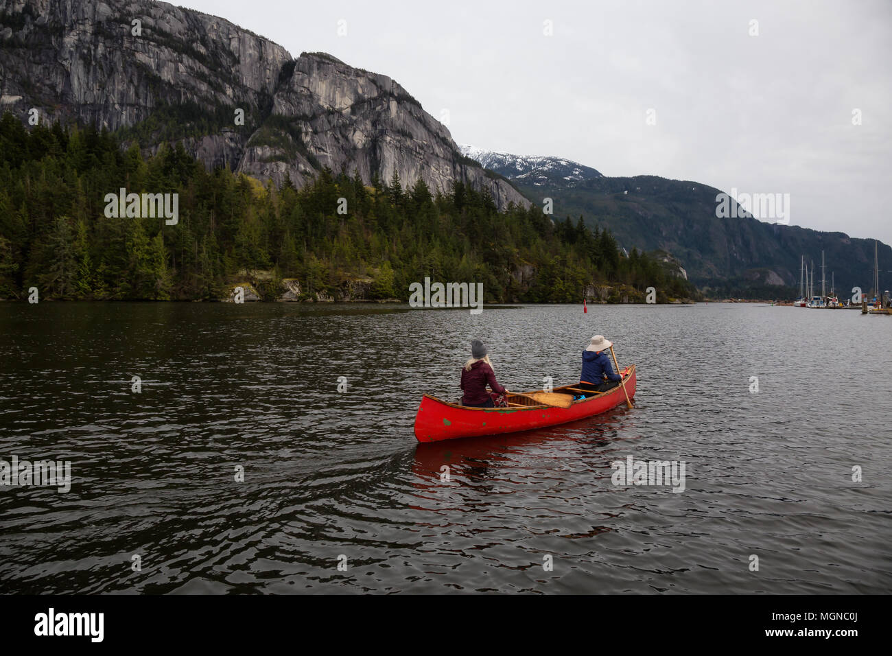 Adventurous people on a wooden canoe are paddling in a river with ...