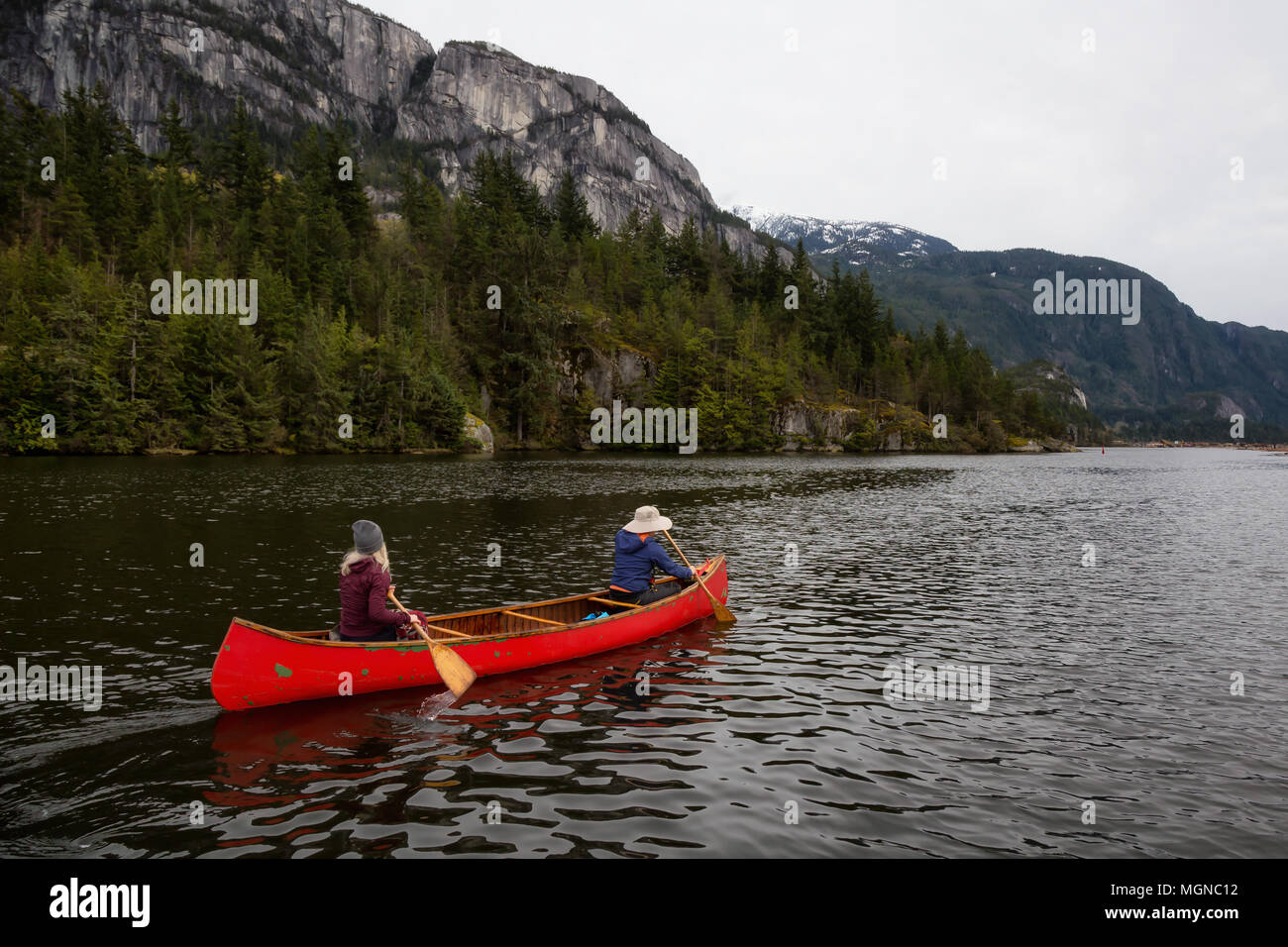 Adventurous people on a wooden canoe are paddling in a river with ...