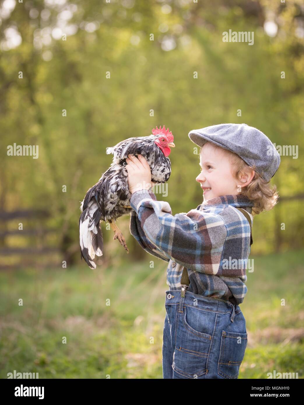 Small boy portrait with chicken. Caucasian curly haired boy in hat ...