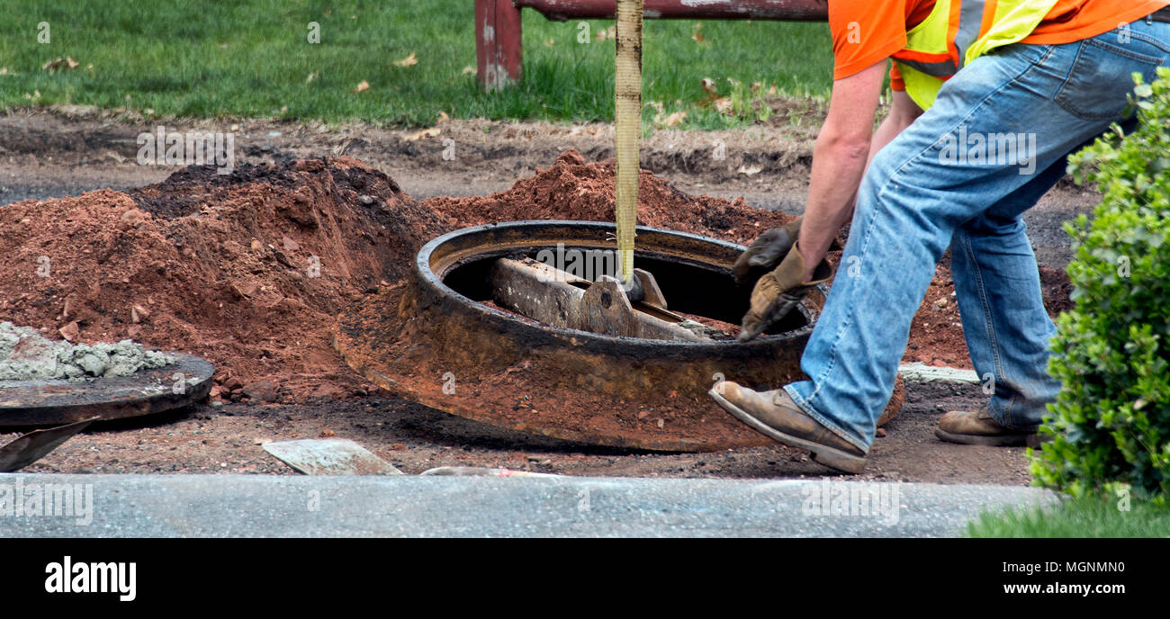 Road resurfacing worker installs a manhole over newly raised surface ...