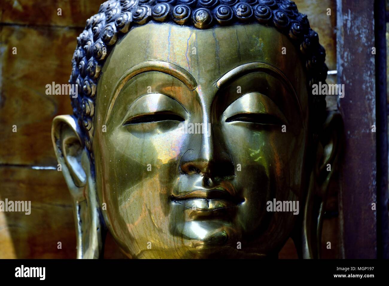 Close up of brass statue of Buddha showing face with serene expression ...