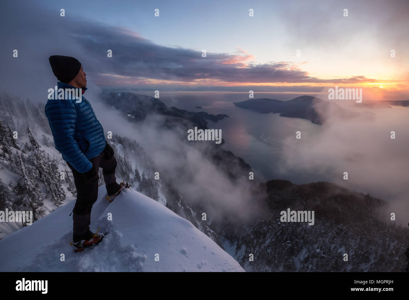 Adventurous man standing on the side of a steep cliff during a ...