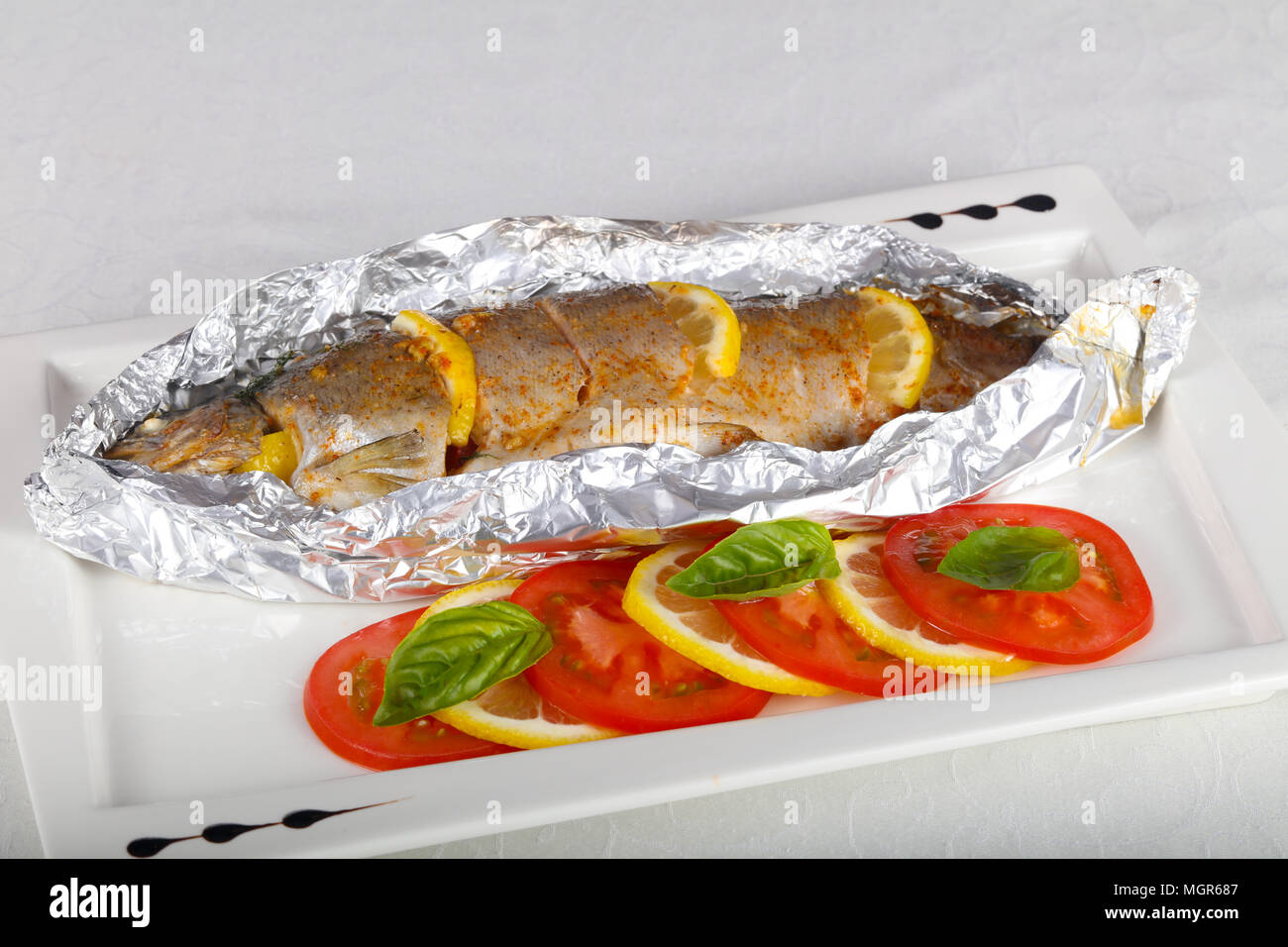 Roasted trout with tomato and lemon Stock Photo - Alamy