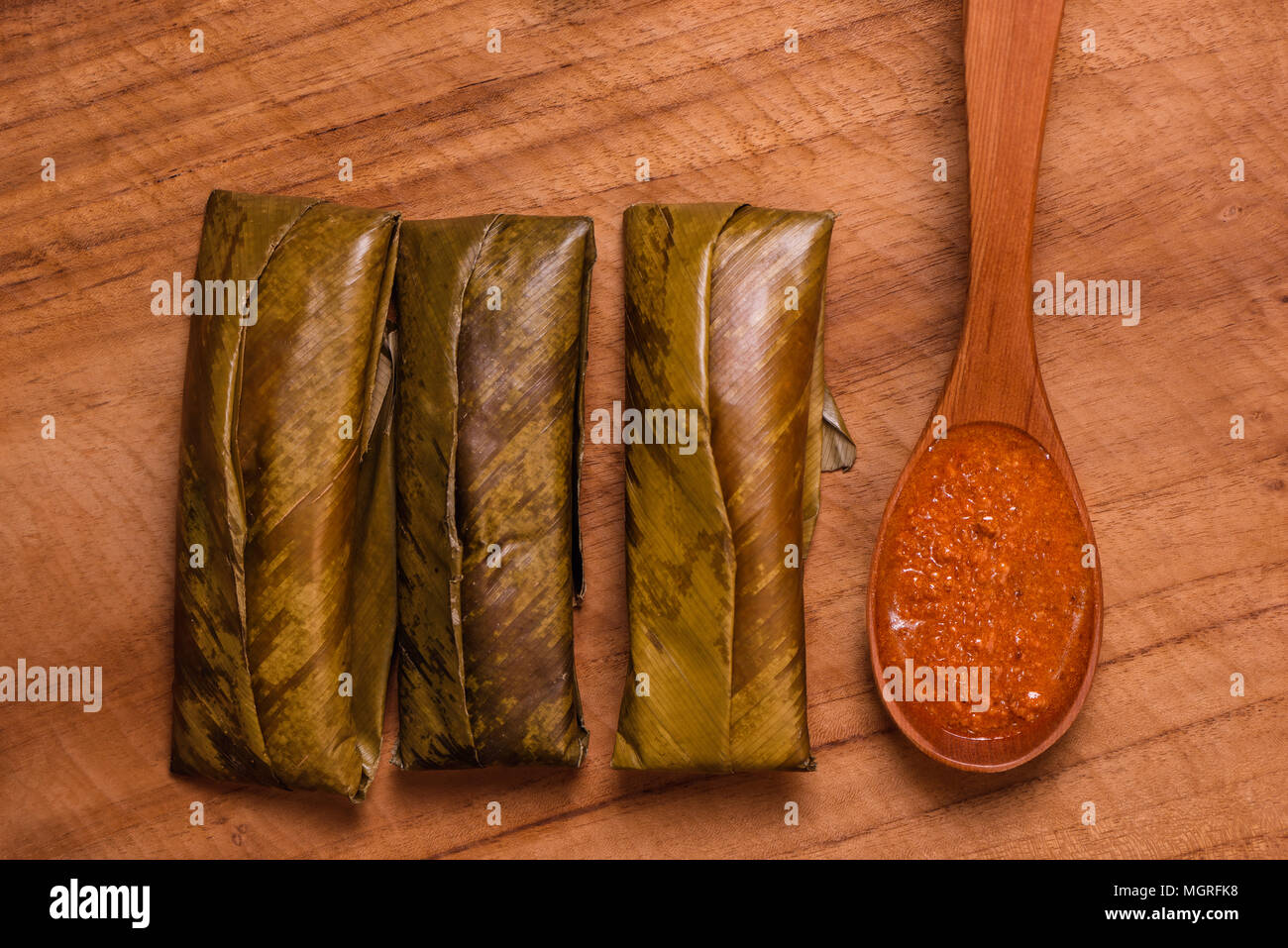 top view of sticky rice wrapped in leaves and served with peanut sauce ...