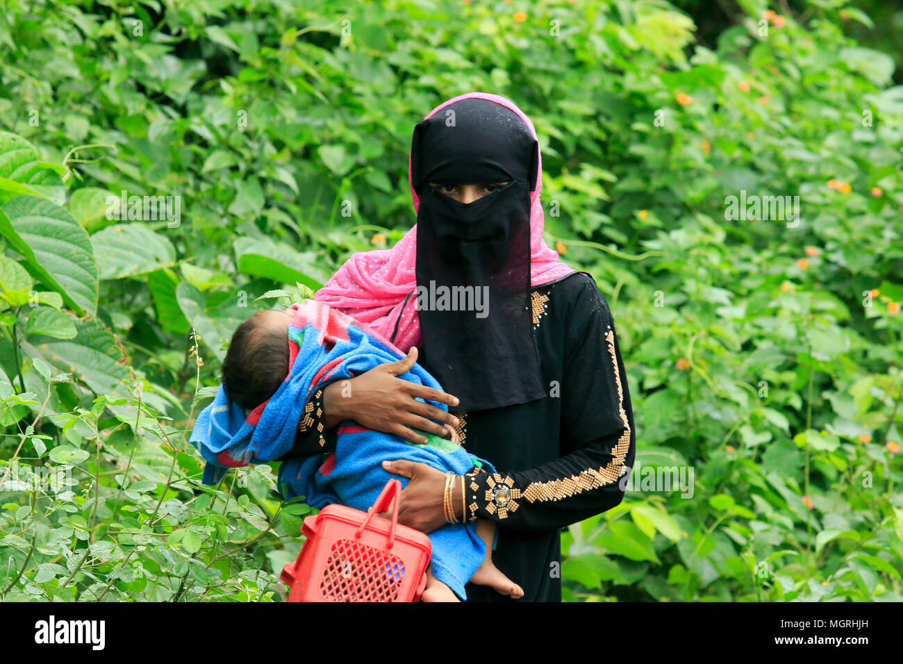 A Rohingya refugee carries her baby through border points in Ukhia ...