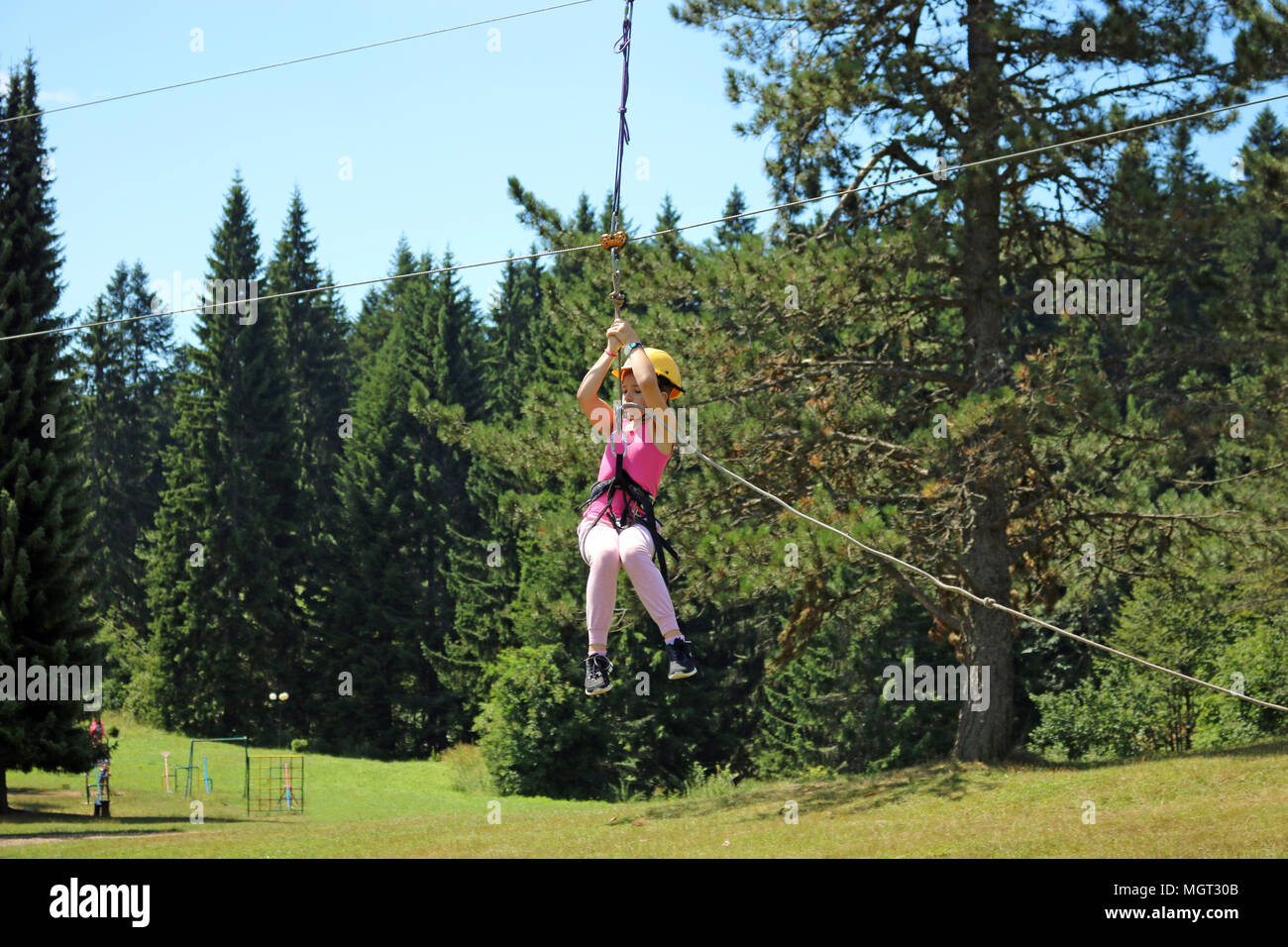 Little girl sliding on a zip line extreme park summer season Stock ...