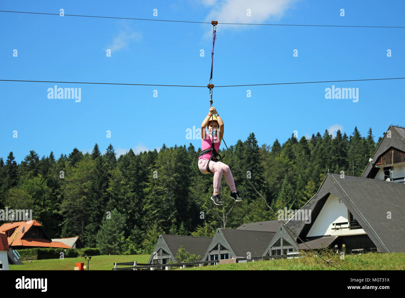 Little girl sliding on a zip line extreme park Stock Photo - Alamy