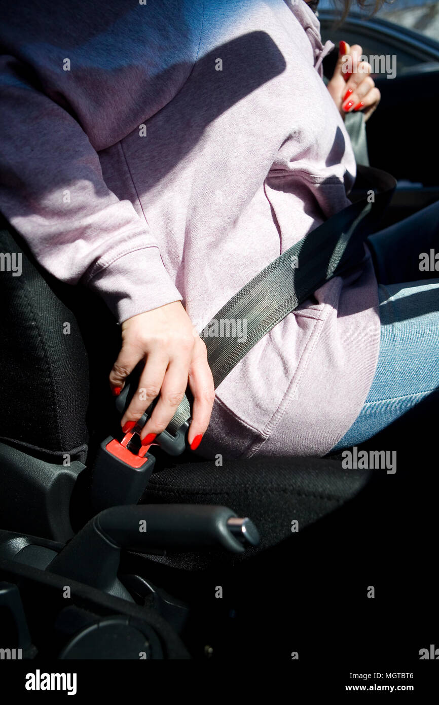 Women's hands with a beautiful manicure fasten the seat belt. Behind ...