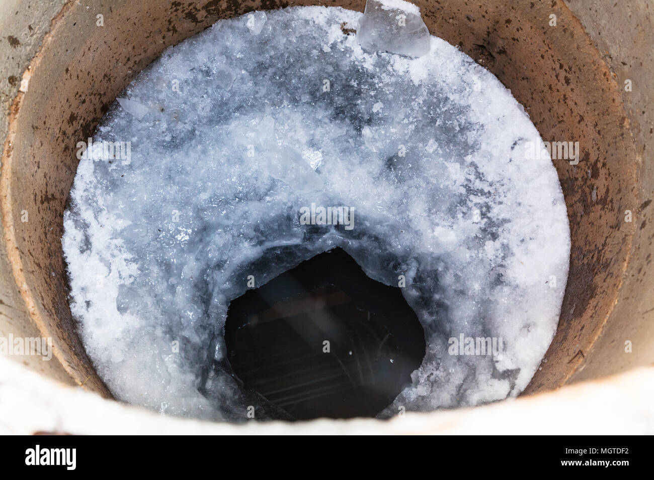 top view of frozen water surface and ice hole in well in cold winter ...