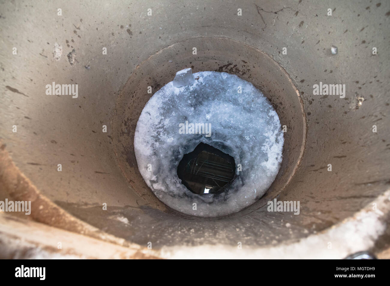 top view of frozen water surface and ice hole in concrete well in cold ...