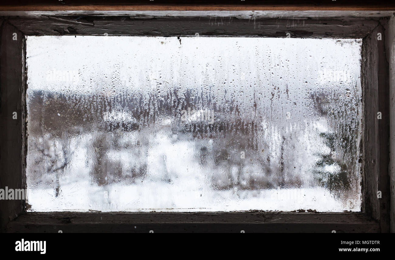 blurry view of russian village through water drops from melting snow on ...