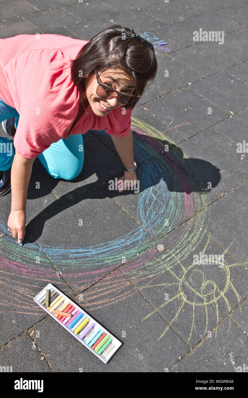 Young woman draw with color chalks on a street. Fun and having good ...