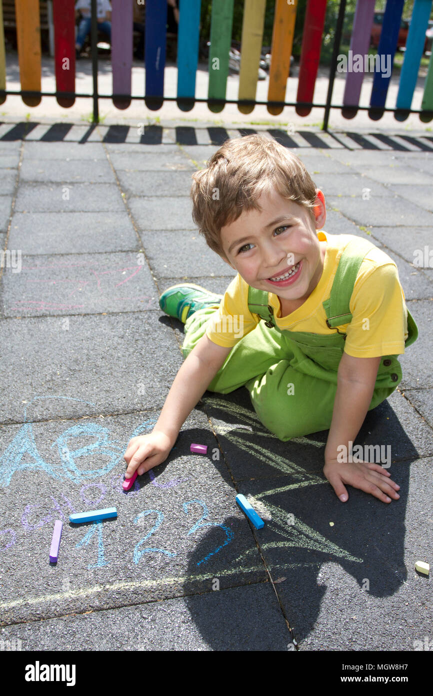 Cute boy write with colored chalks. Little kid draws with chalks ...