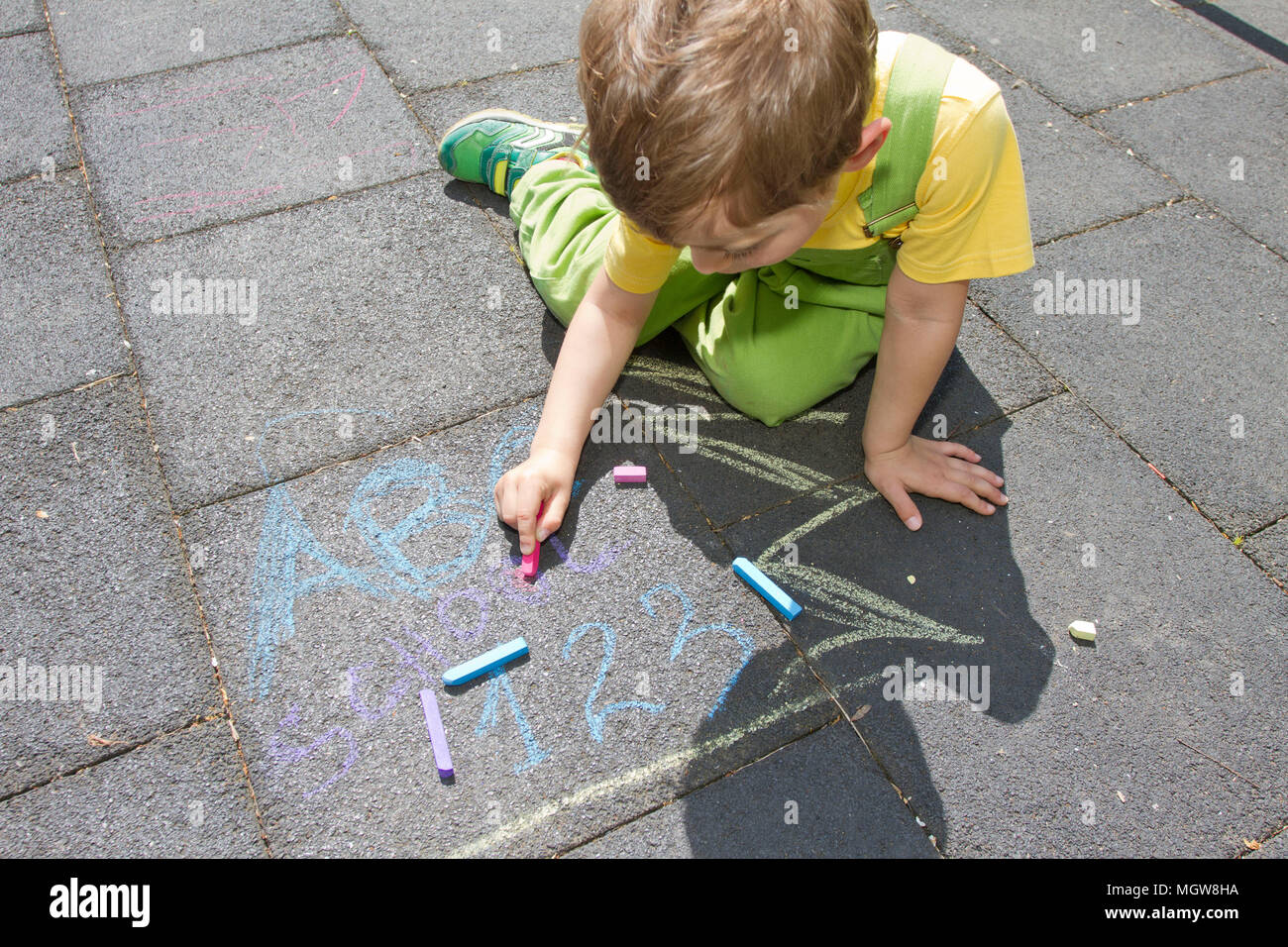 Cute boy write with colored chalks. Little kid draws with chalks ...
