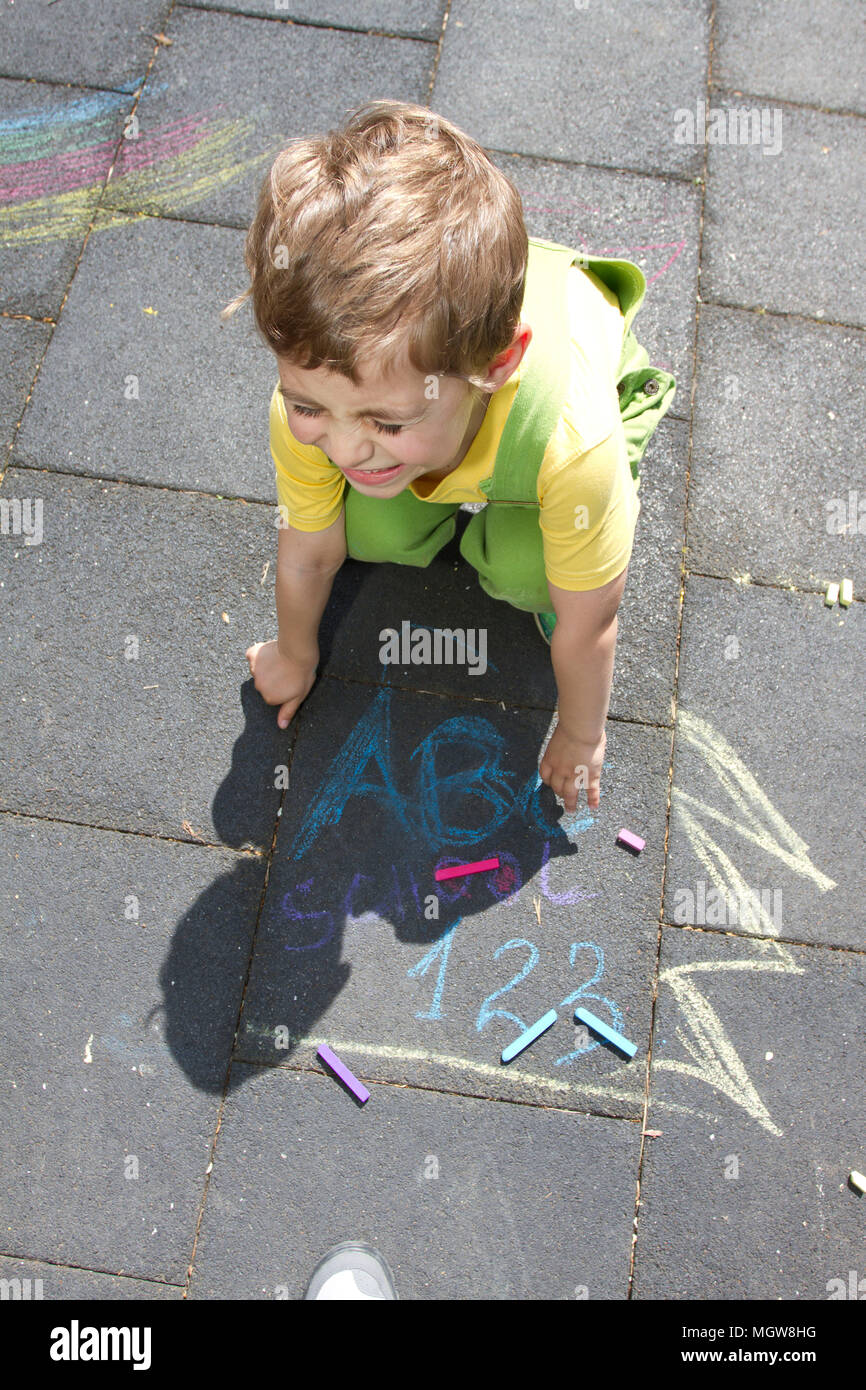 Cute boy write with colored chalks. Little kid draws with chalks ...