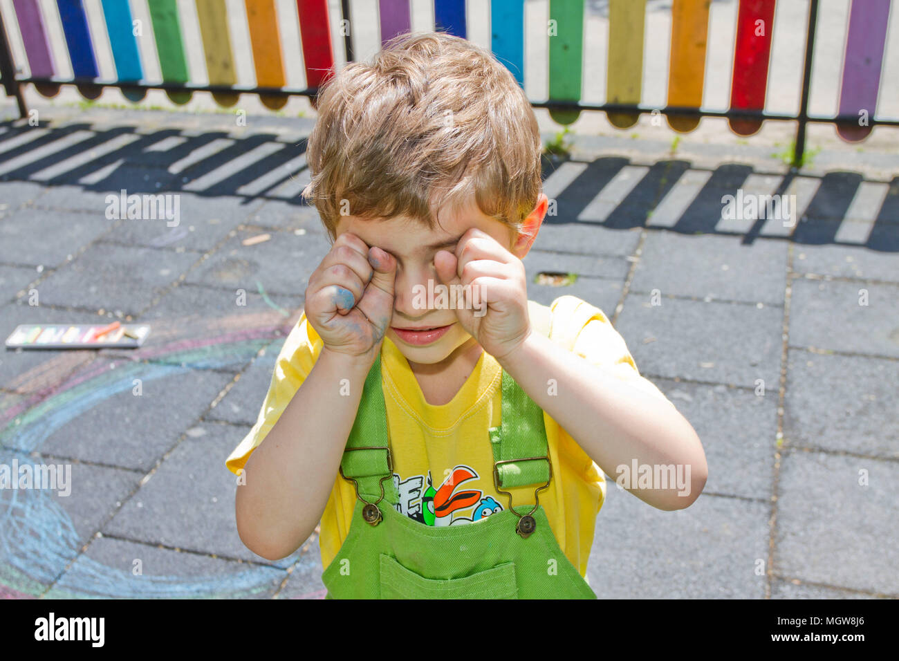 Cute boy cries. Kid cries on a playground. A child rubbed his eyes. A ...