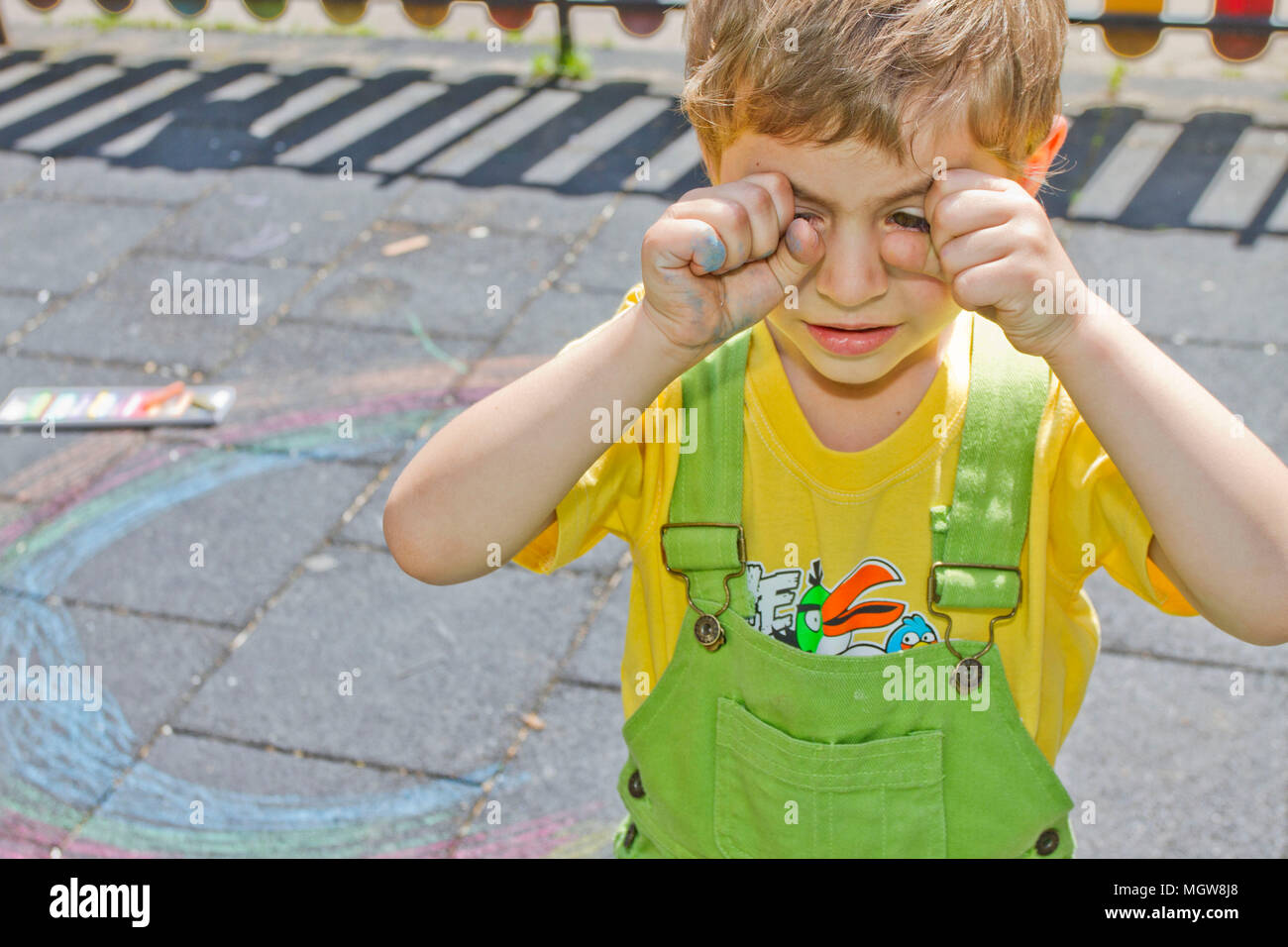 Cute boy cries. Kid cries on a playground. A child rubbed his eyes. A ...