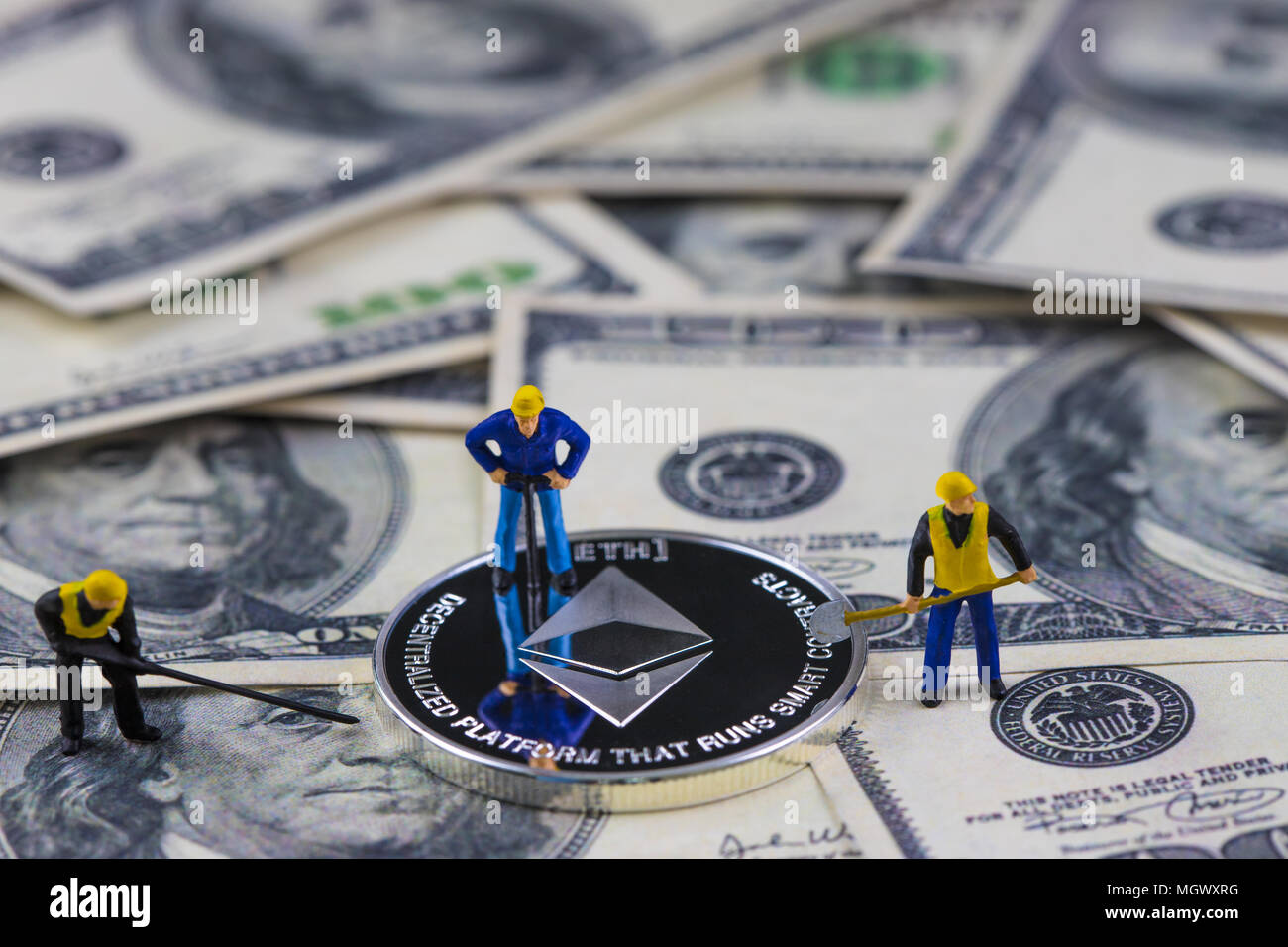 Miniature people worker digging silver ethereum coin on hundred dollar ...