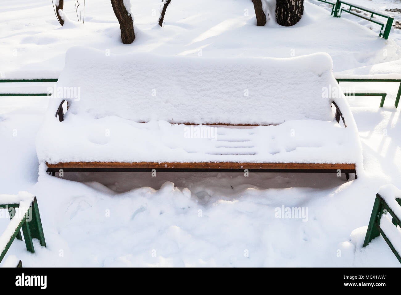 snow-covered bench at urban square in Moscow city in winter morning ...