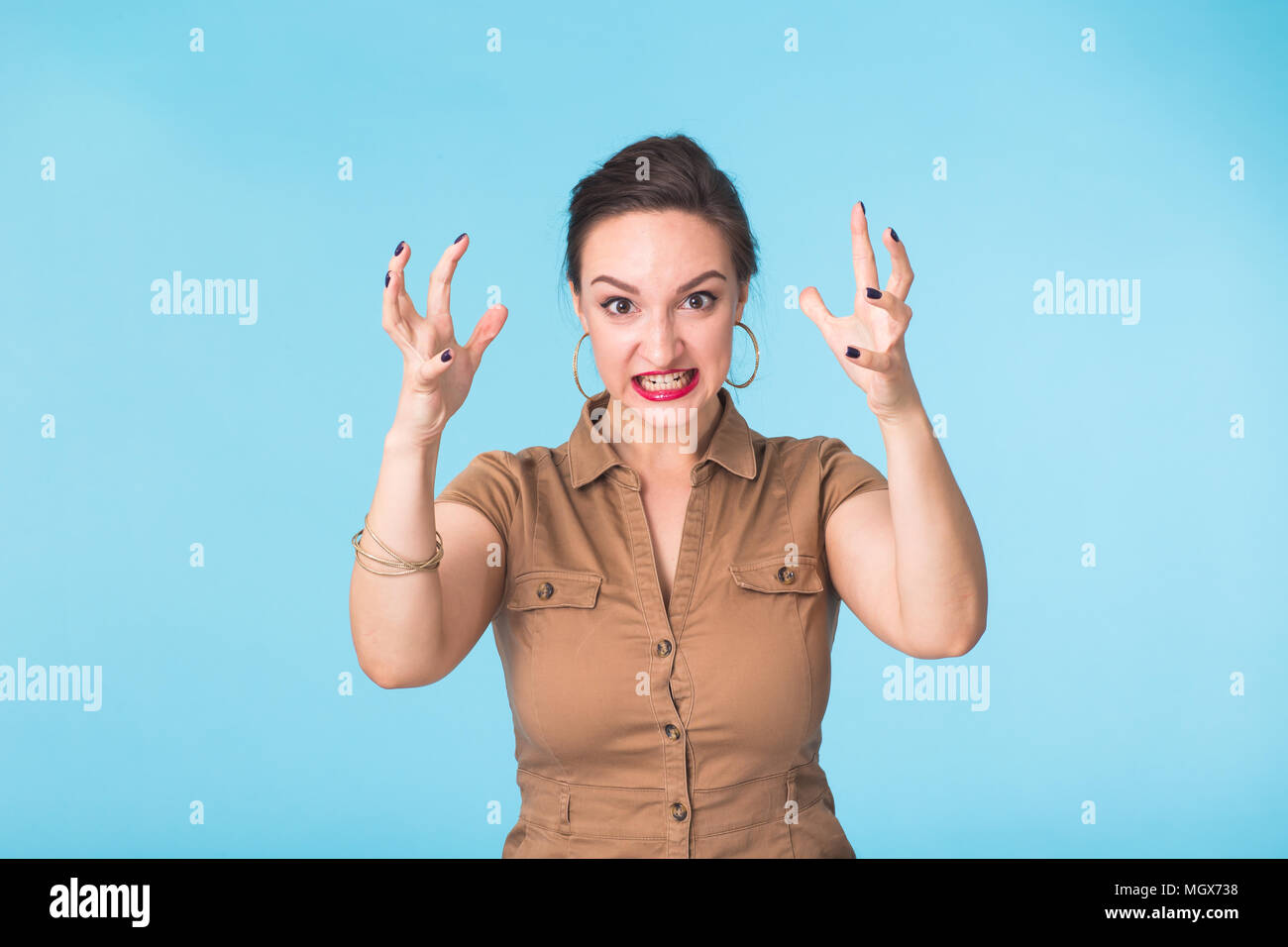 Angry aggressive woman with ferocious expression on blue background ...