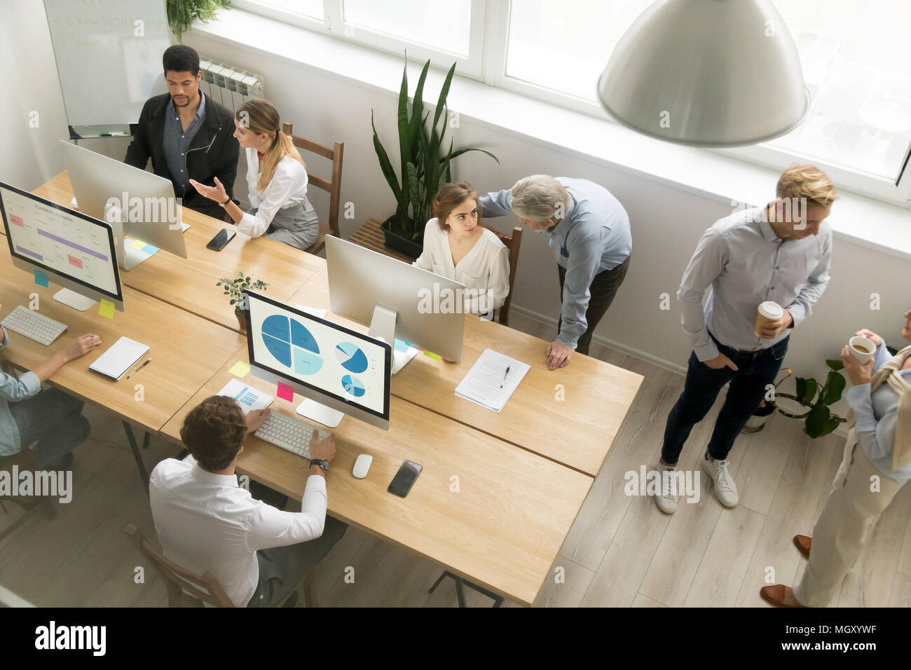 Office employees working together sharing desk using computers i Stock ...
