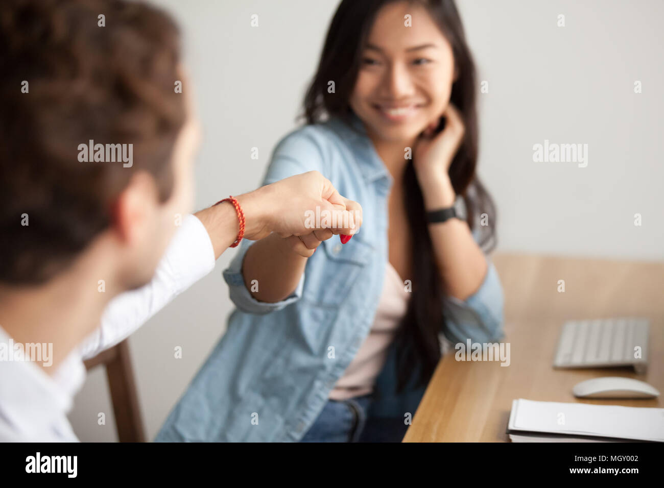 Smiling asian young woman fist bumping male colleague at work Stock ...