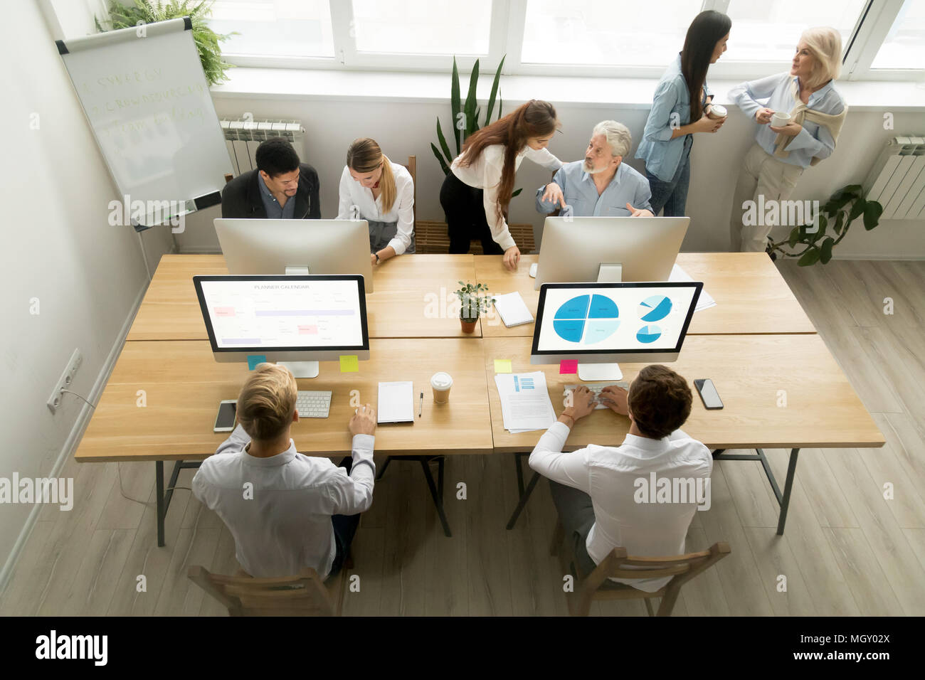 Corporate staff working in office together using computers and t Stock ...