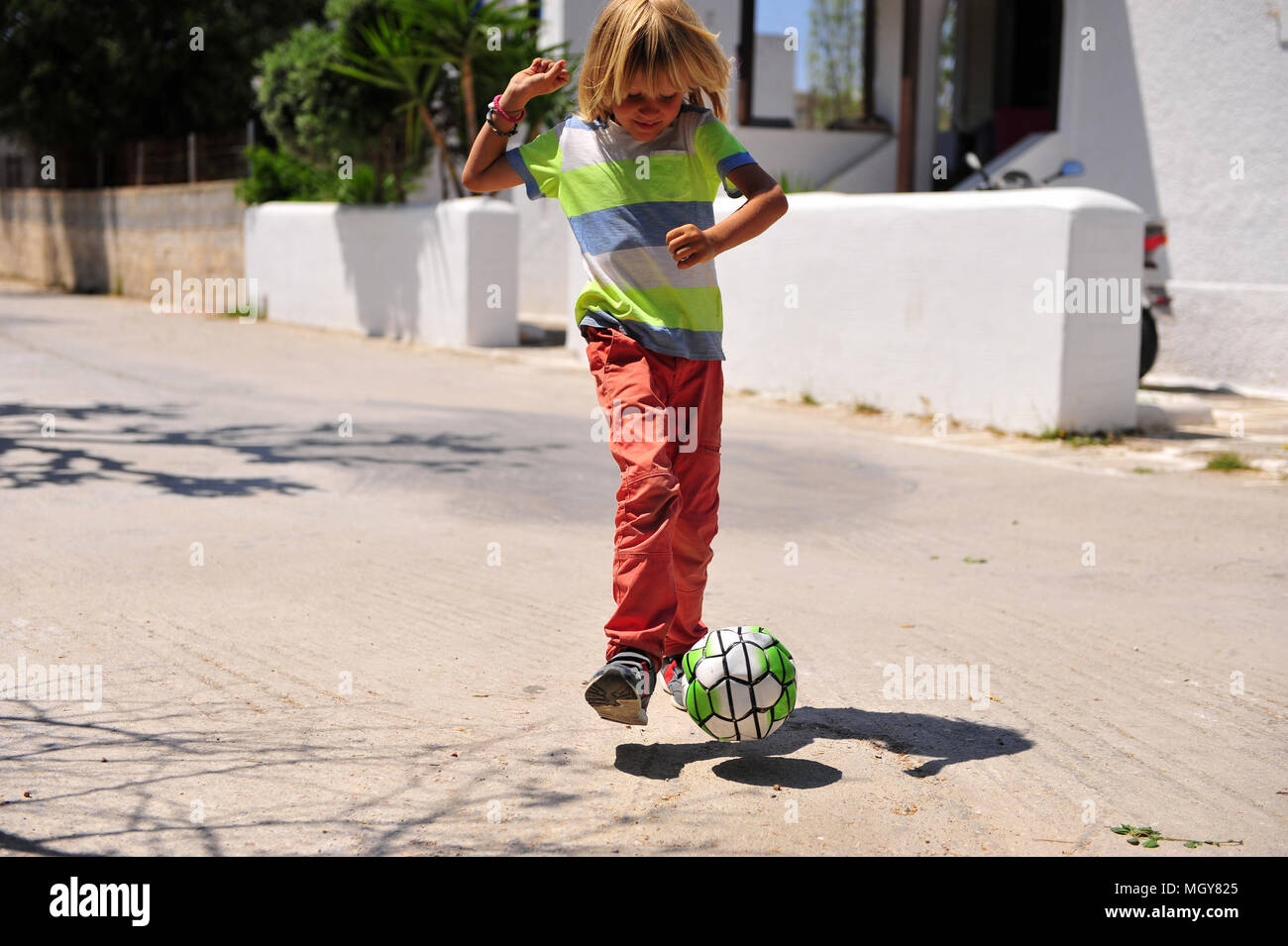 Boy playing with ball in the street Stock Photo - Alamy