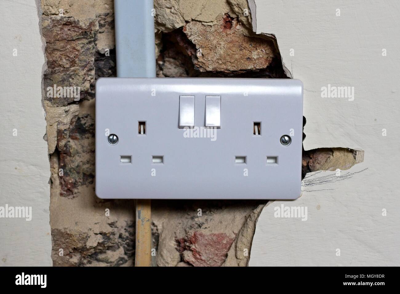 Double/twin electric wall socket showing exposed bricks, cabling ...