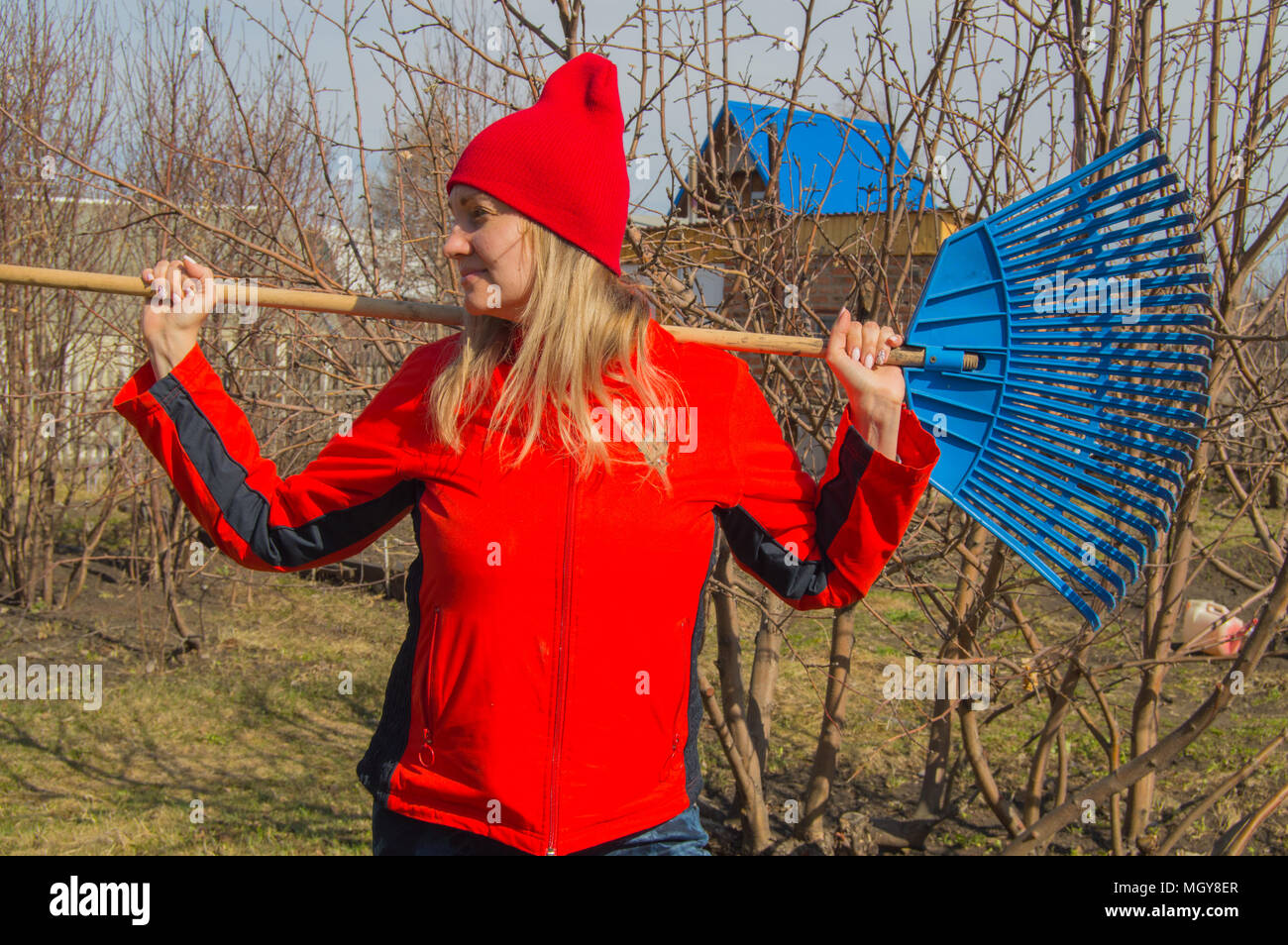 Happy smiling beautiful girl posing with rakes. Garden and outdoor work ...