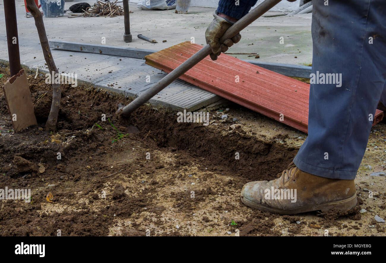 Worker digging a ditch with a hoe in a construction in a rural place ...