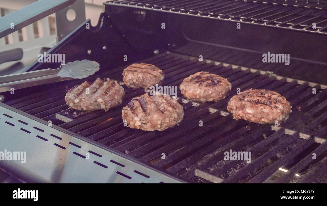 Cooking classic beef burger on outdoor gas grill Stock Photo - Alamy
