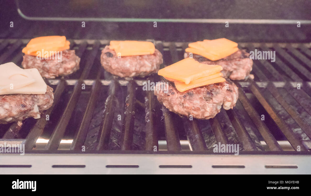 Cooking classic beef burger on outdoor gas grill Stock Photo - Alamy
