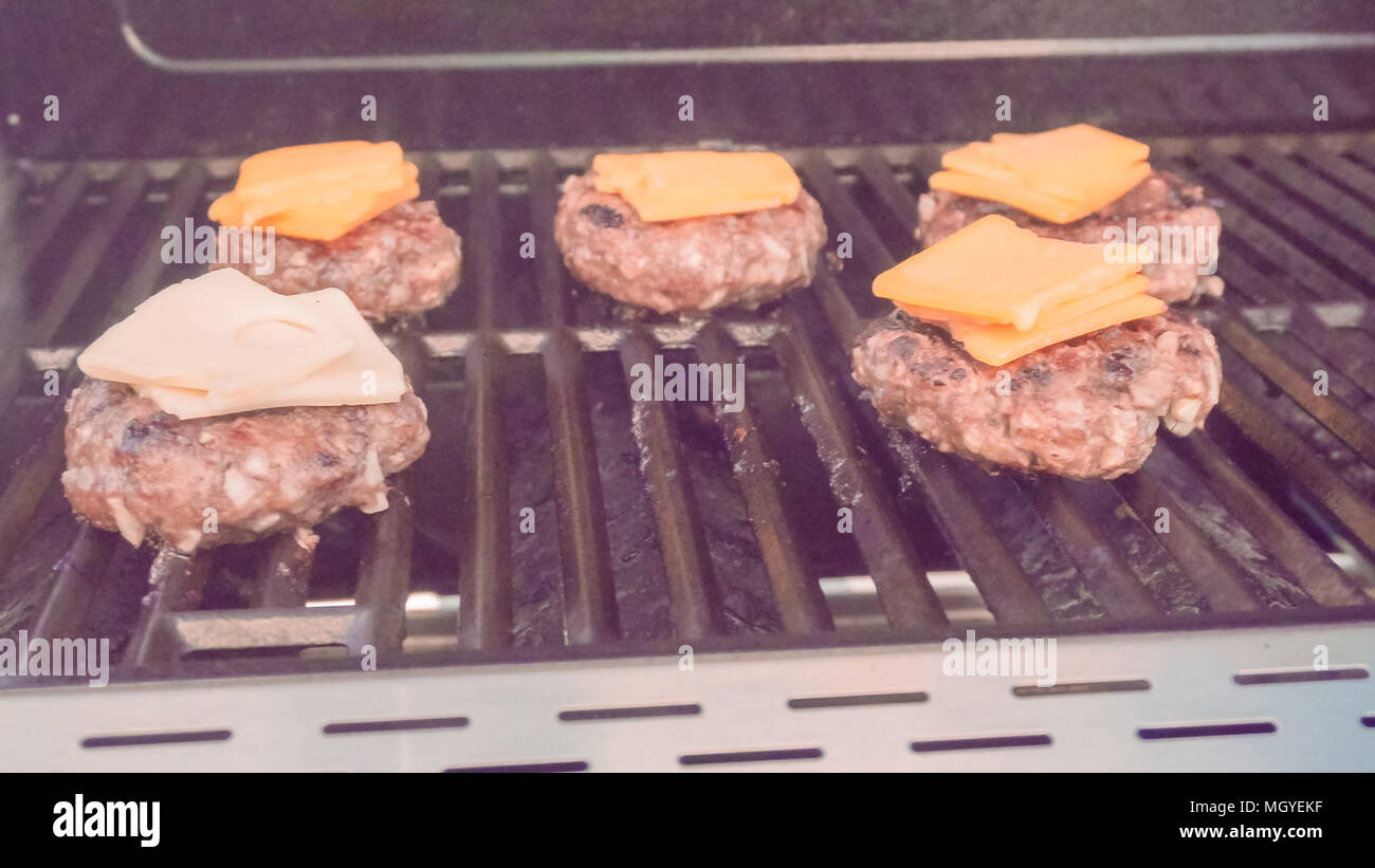 Cooking classic beef burger on outdoor gas grill Stock Photo - Alamy