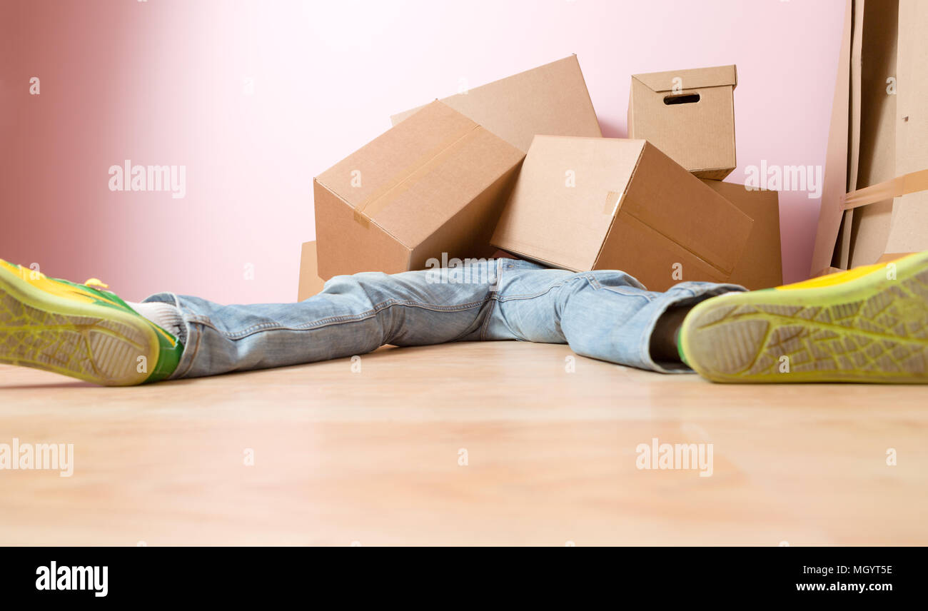 Image of man in jeans lying under cardboard boxes Stock Photo - Alamy