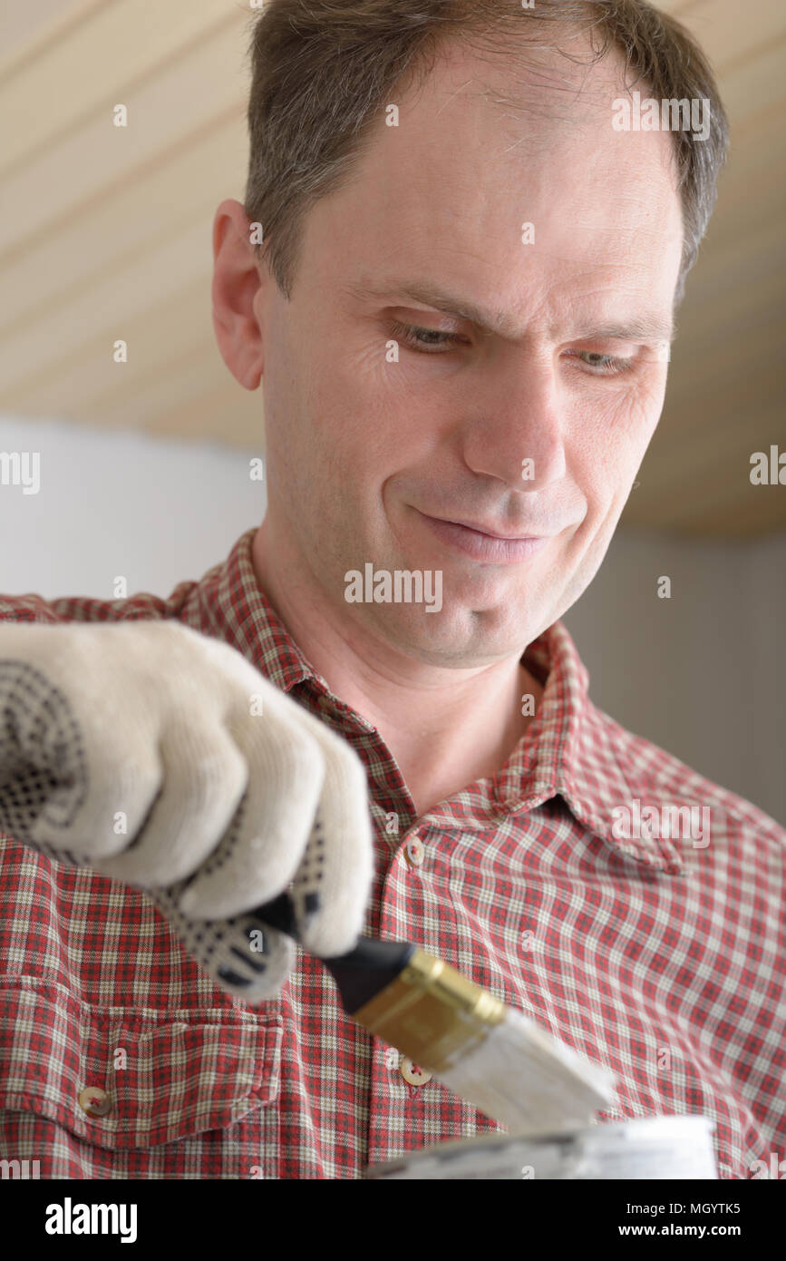 Mature contractor with paintbrush against wooden ceiling Stock Photo ...