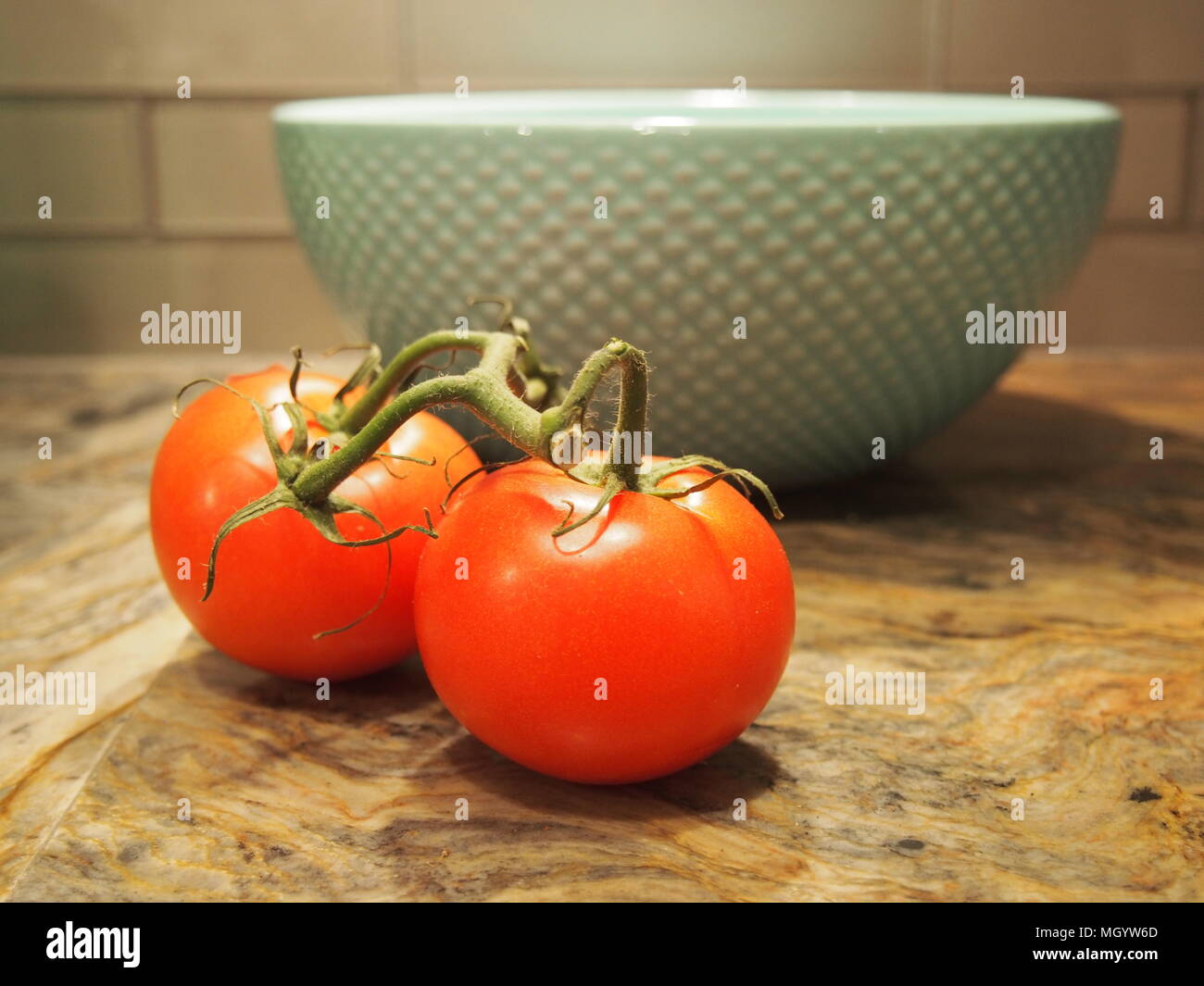 Tomatoes on the vine and green bowl on kitchen countertop, USA 2017 ...
