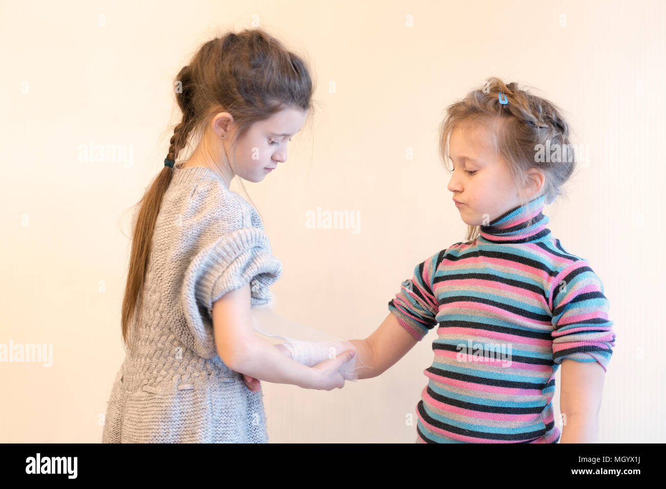 The girl bending her sister's hand. Two, girls, play, doctor. Bandage ...
