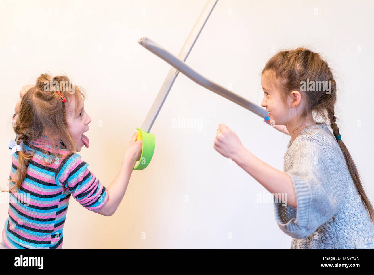 Two girls with toy swords play knights. Children's emotions Stock Photo ...