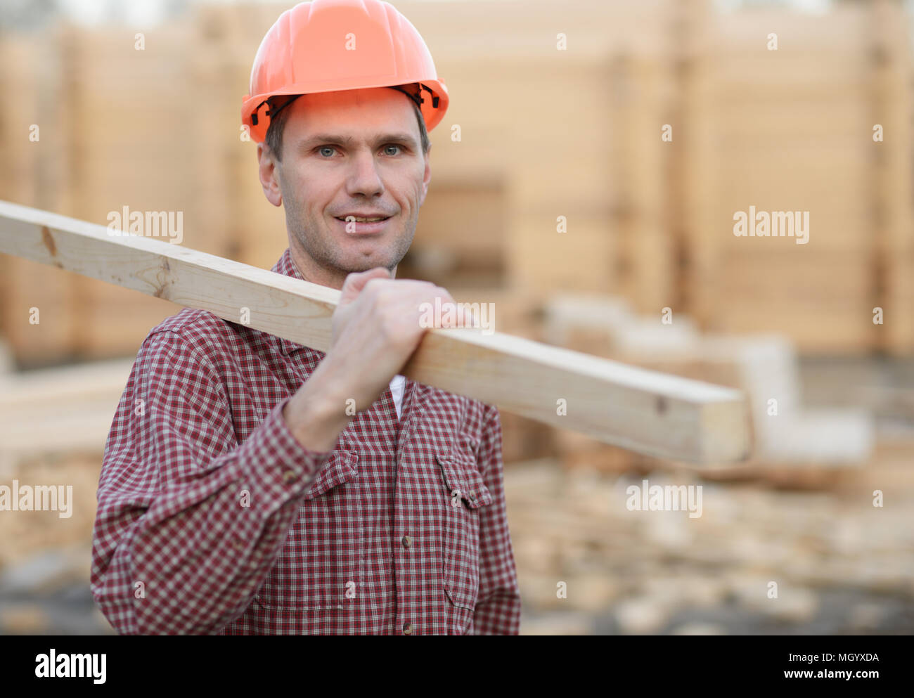 Worker with plank on a construction site Stock Photo - Alamy