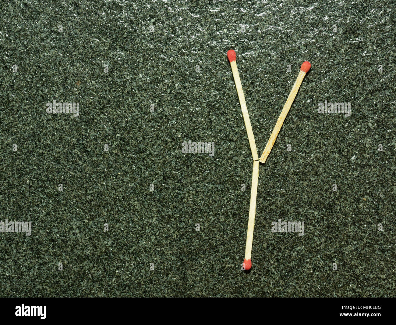 Three wooden match sticks with red head put in Y shape over black or ...