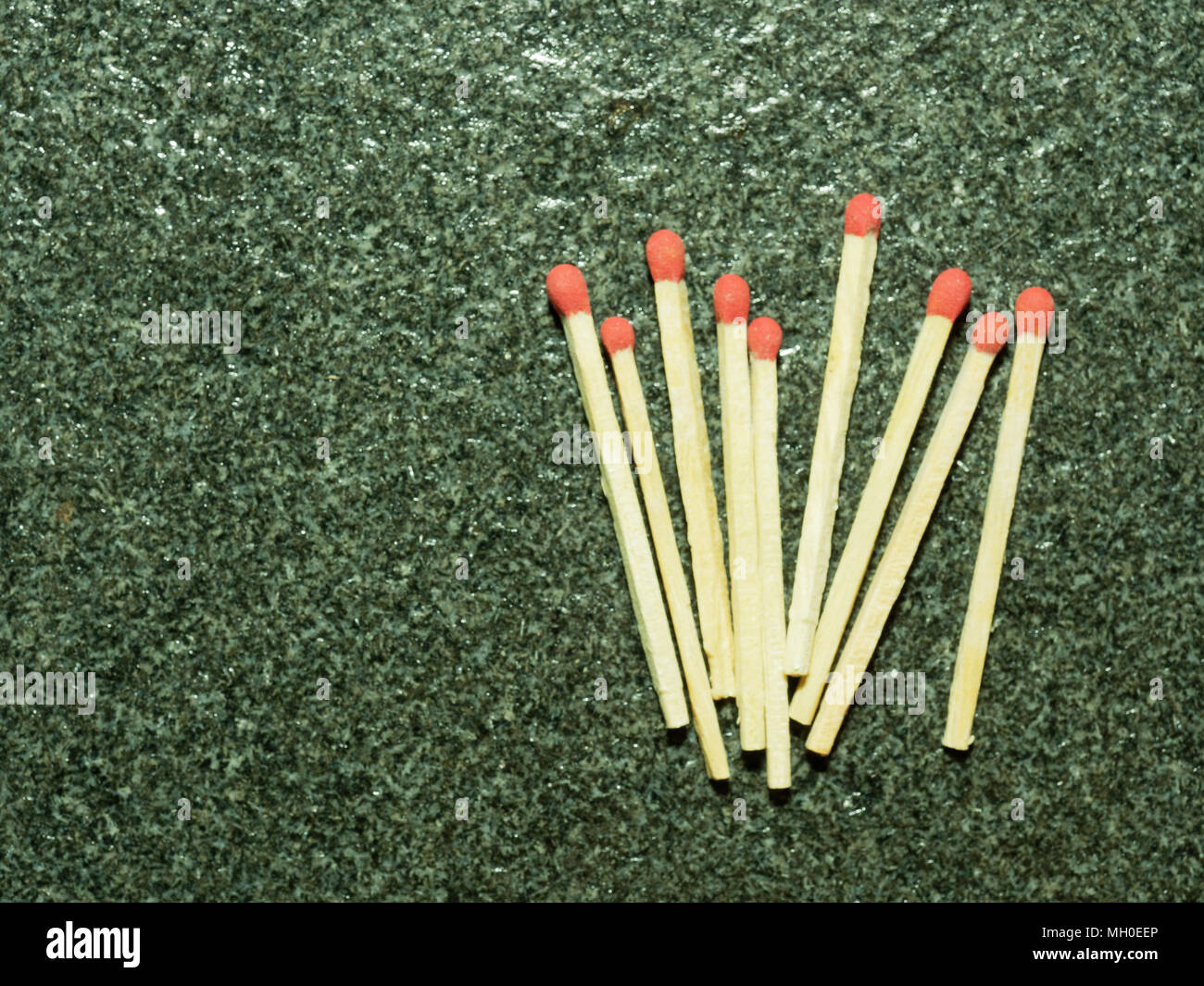 Four wooden match sticks with red head over black or dark granite ...
