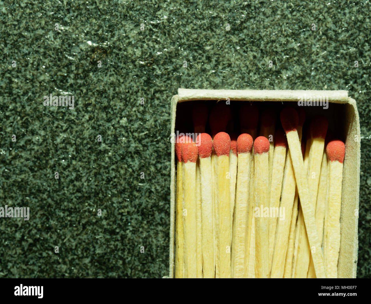 A group of wooden match sticks with red head in match box over black or ...