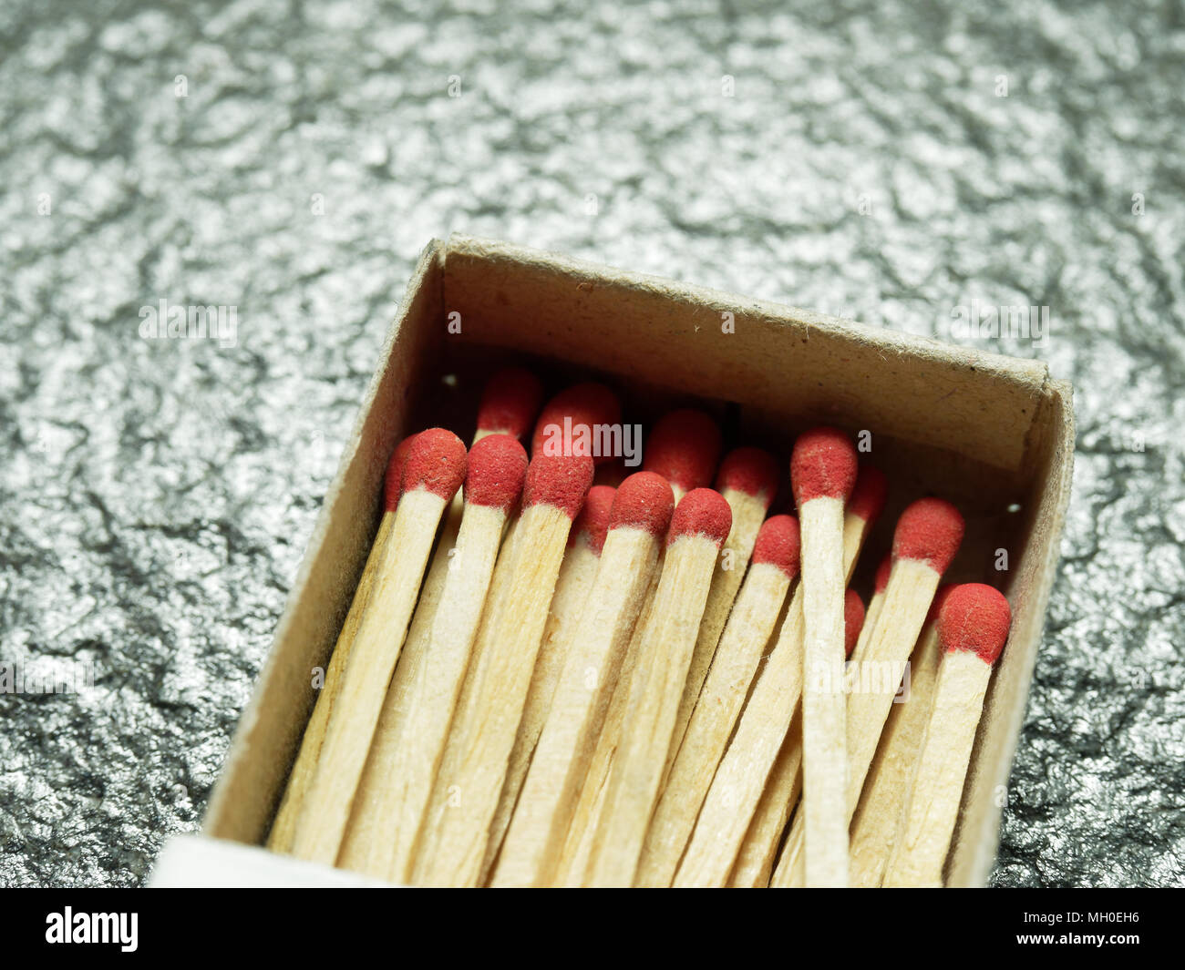 A group of wooden match sticks with red head in match box over black or ...