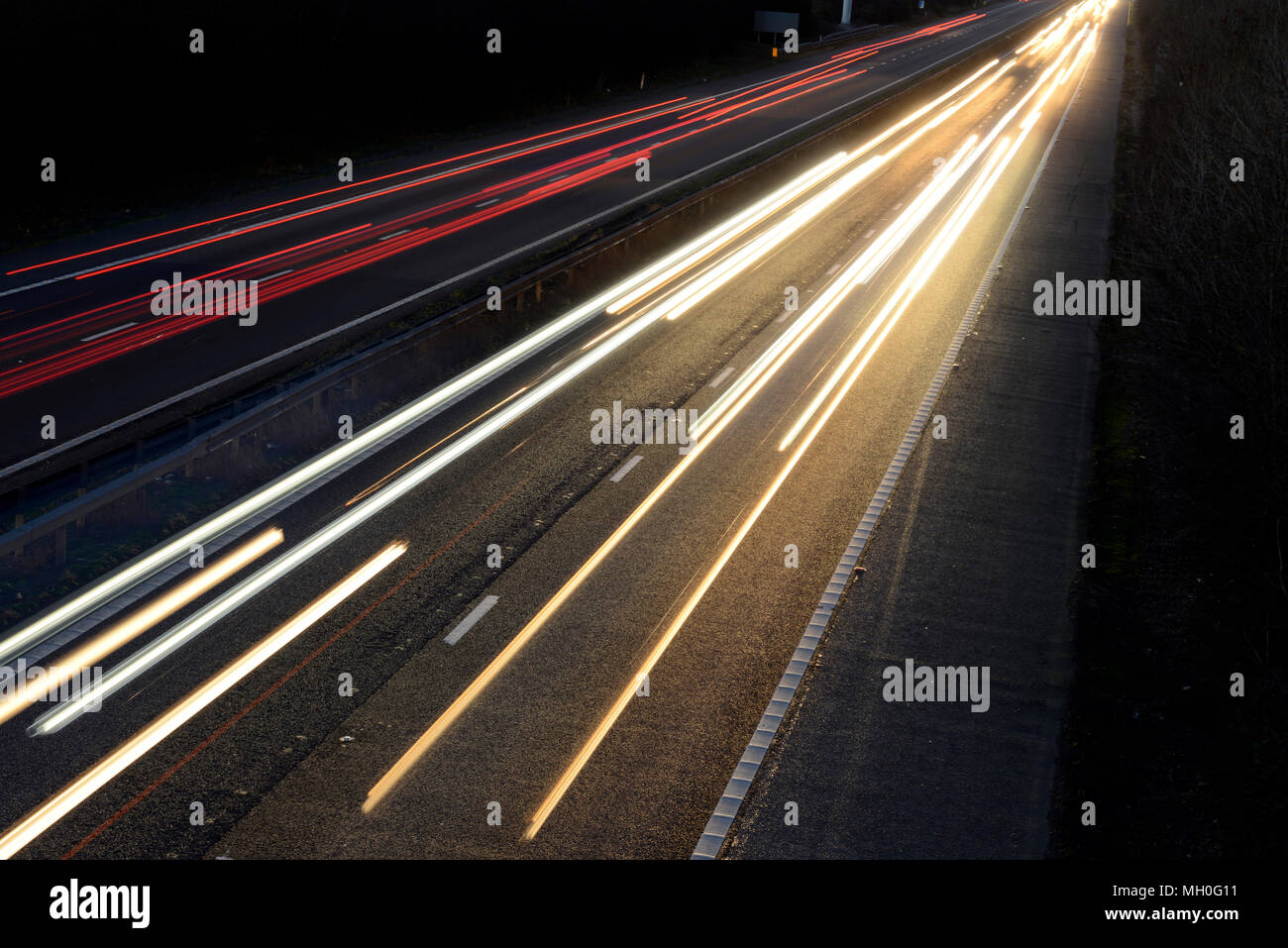 White headlights and red tail-lights on motorway at night in motion ...
