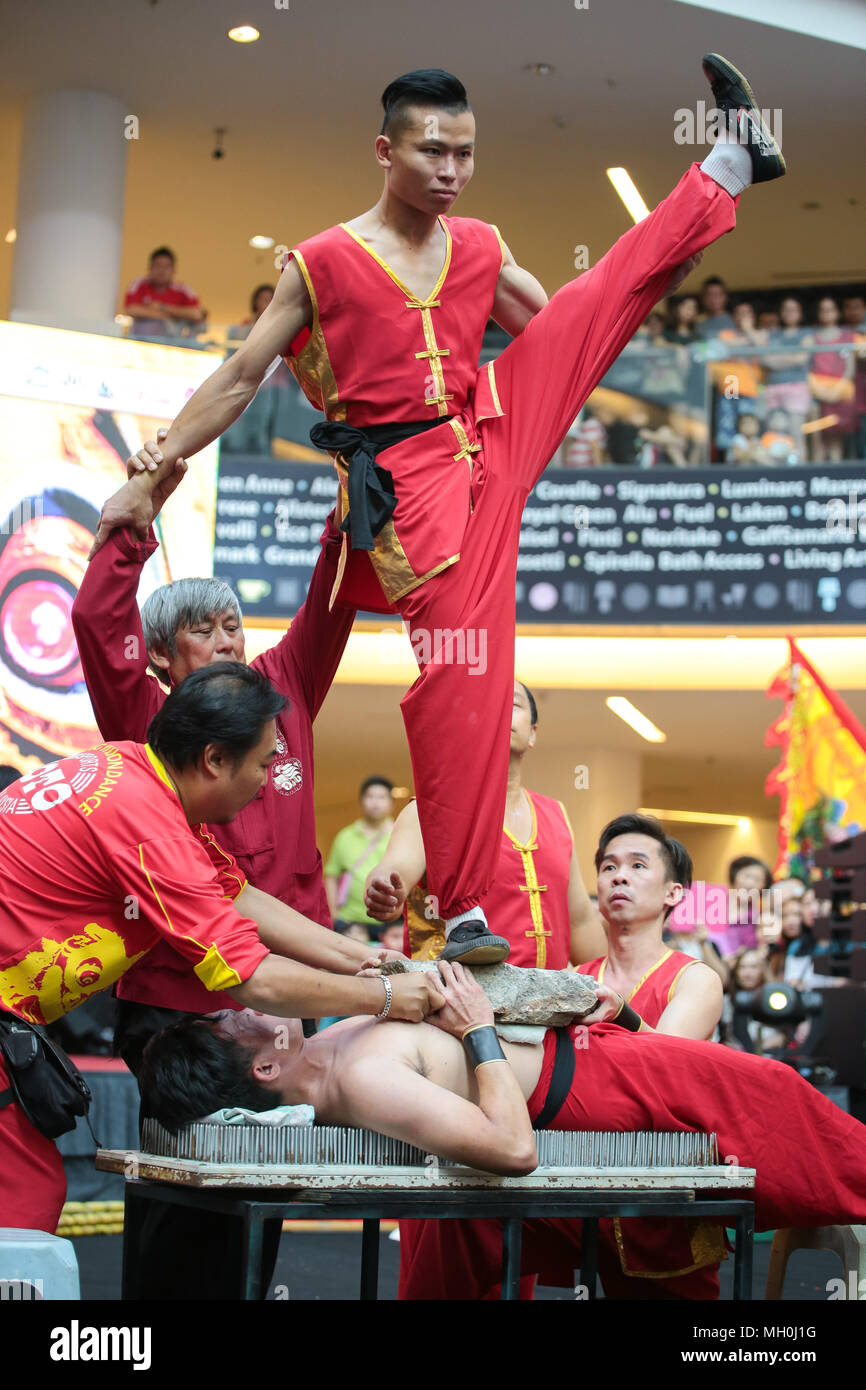 Chinese traditional stuntman stand on his coleague lying on needle bed ...