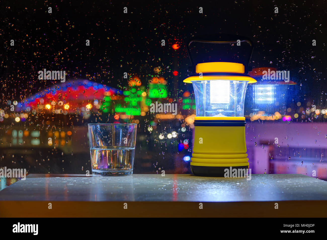 Luminous hand lantern standing near a wet window on the background of ...